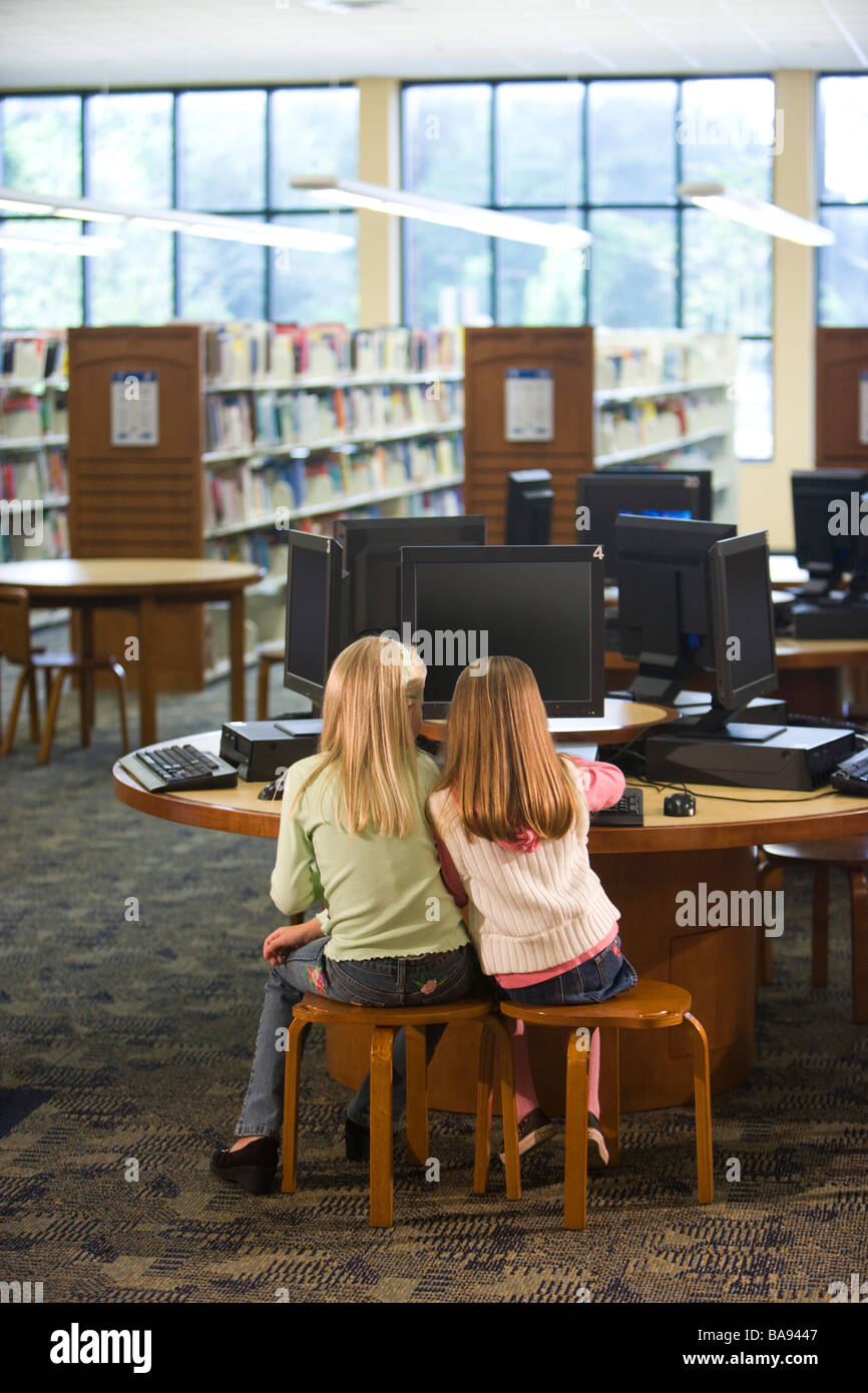 Two elementary school girls using computer in library, rear view Stock ...