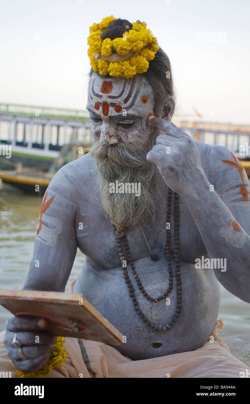 An Indian Saddhu covered in ash applying face paint at Varanasi, India ...