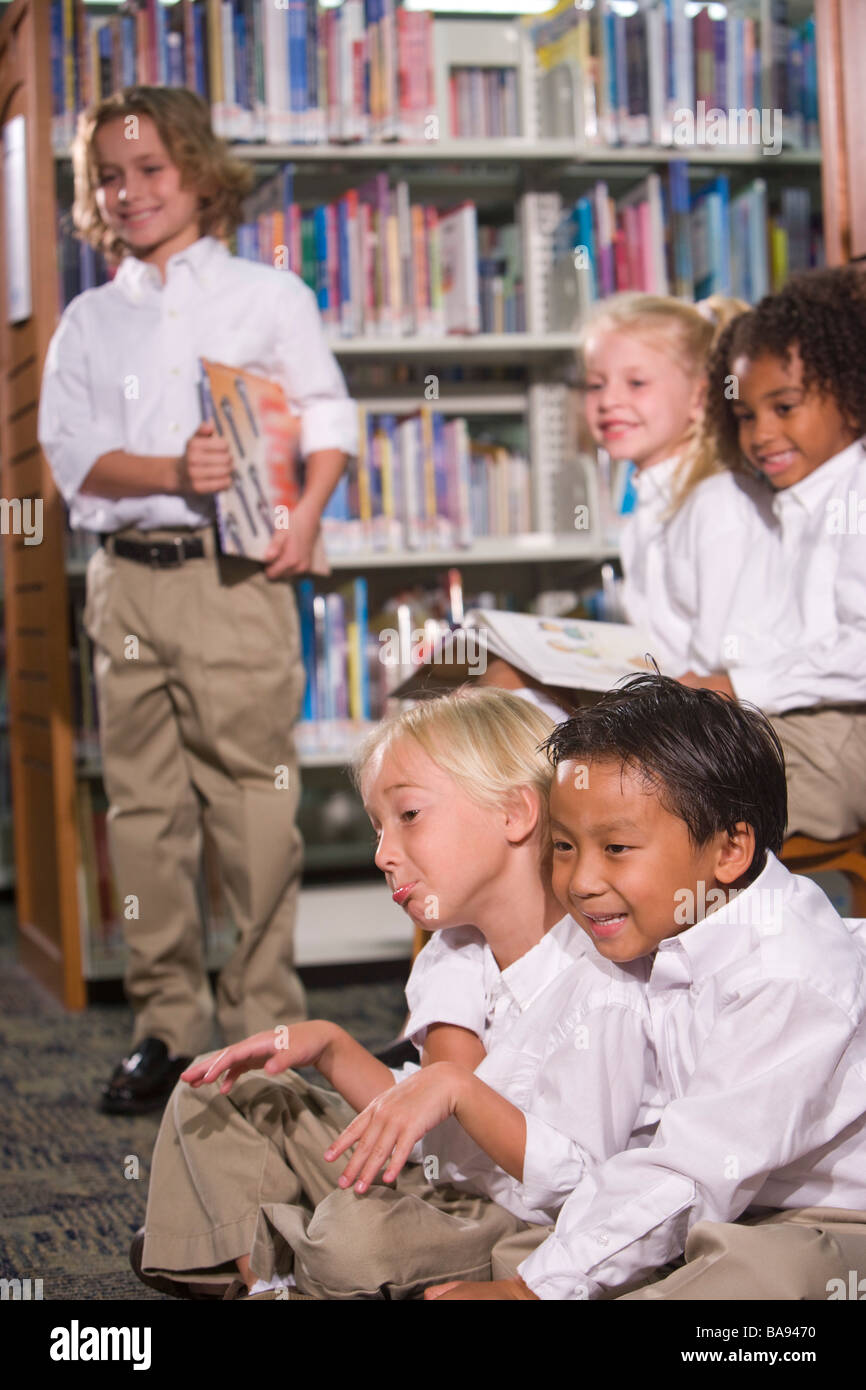 Five elementary school children sitting in library Stock Photo - Alamy