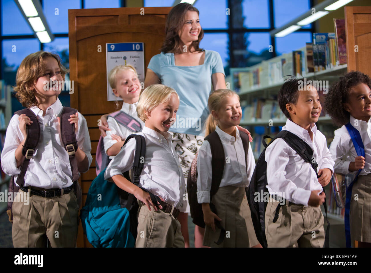 Elementary school teacher with class in library Stock Photo - Alamy