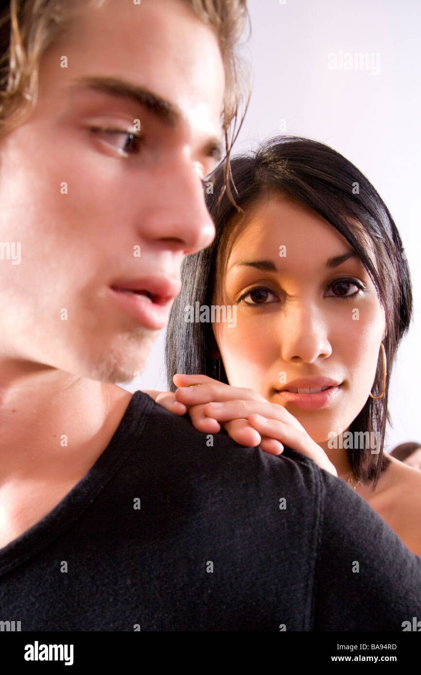 Close-up of serious young man glancing back at young woman Stock Photo ...