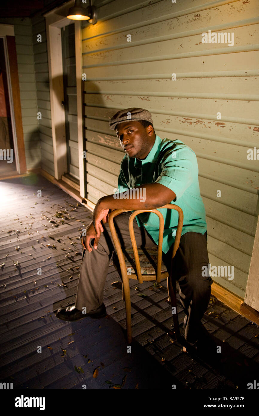 Portrait of African American man sitting on porch of house at night ...
