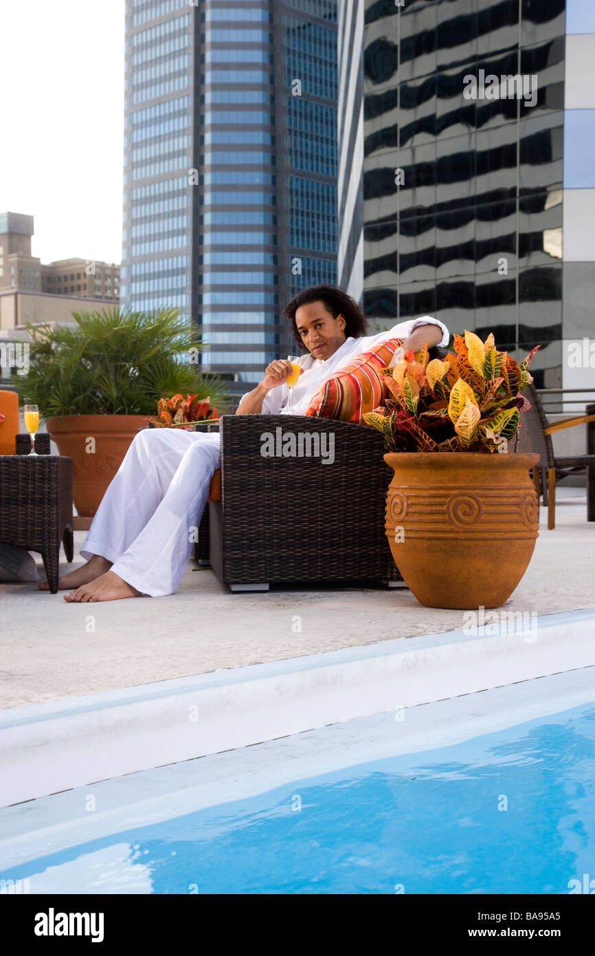 African-American man on rooftop terrace by swimming pool in city Stock ...