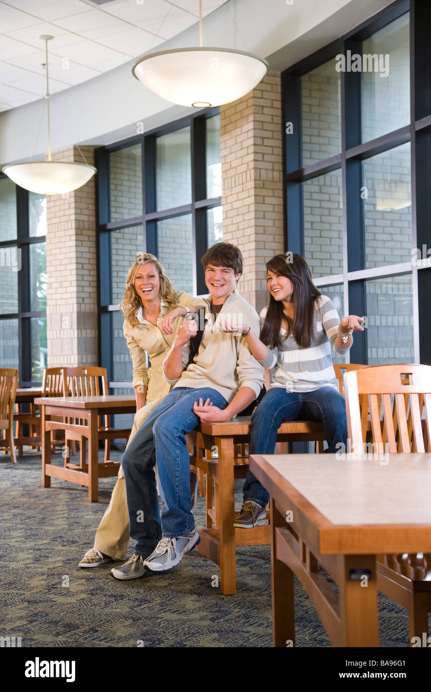 Teenagers sitting on table in library Stock Photo - Alamy