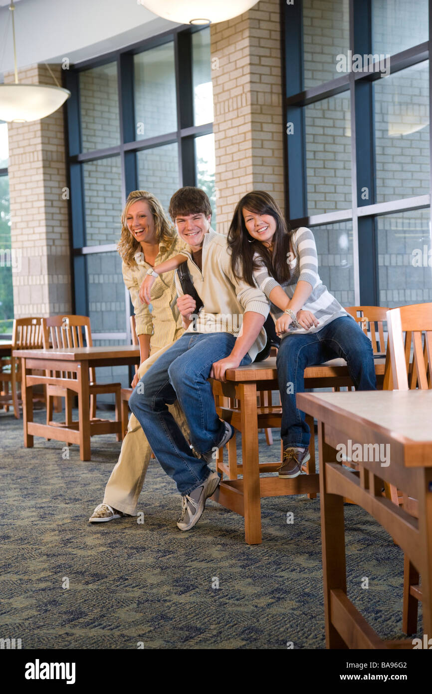 Teenagers sitting on table in library Stock Photo - Alamy