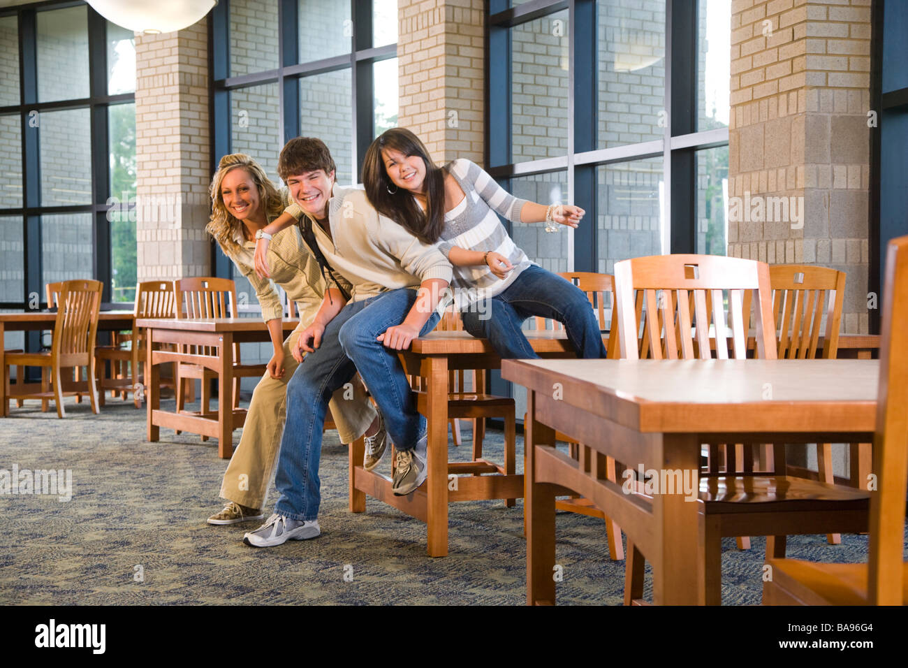 Teenagers sitting on table in library Stock Photo - Alamy