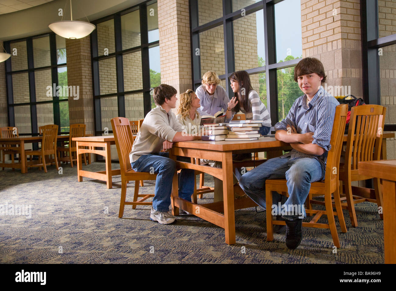 Teenage students sitting at table in library Stock Photo - Alamy