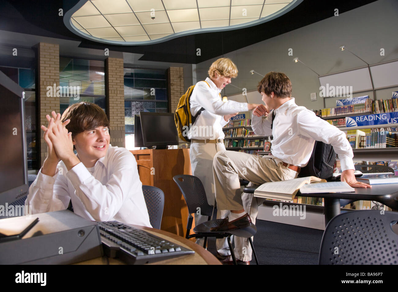 Three teenage student boys in library Stock Photo - Alamy