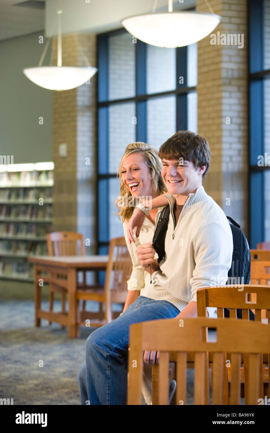 Teenage students sitting on table in library Stock Photo - Alamy