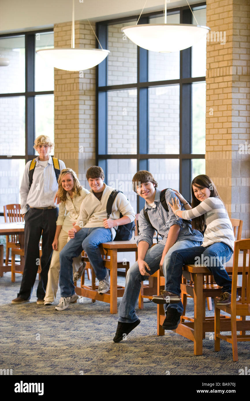 Five teenage students sitting on table in library Stock Photo - Alamy