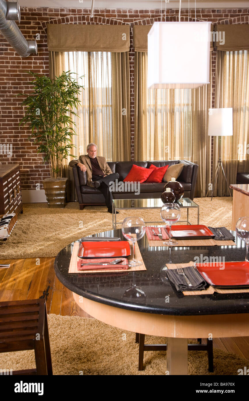 Middle-aged man sitting on couch in modern downtown loft Stock Photo ...