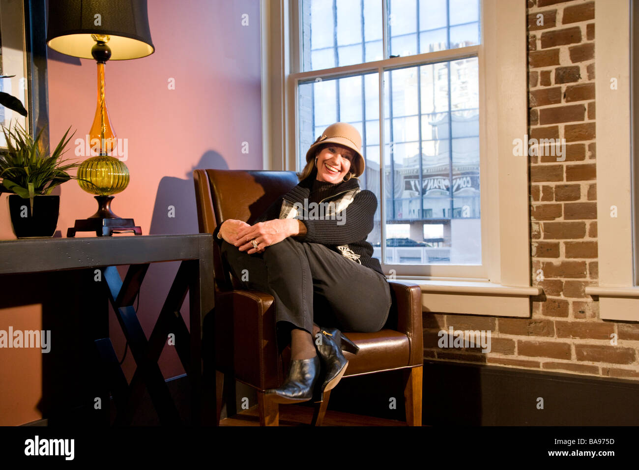 Middle-aged woman sitting in modern downtown loft Stock Photo - Alamy