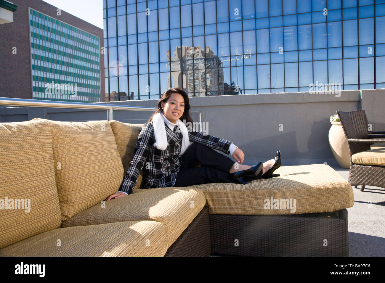 Young Asian woman sitting on rooftop of downtown condo in city Stock ...