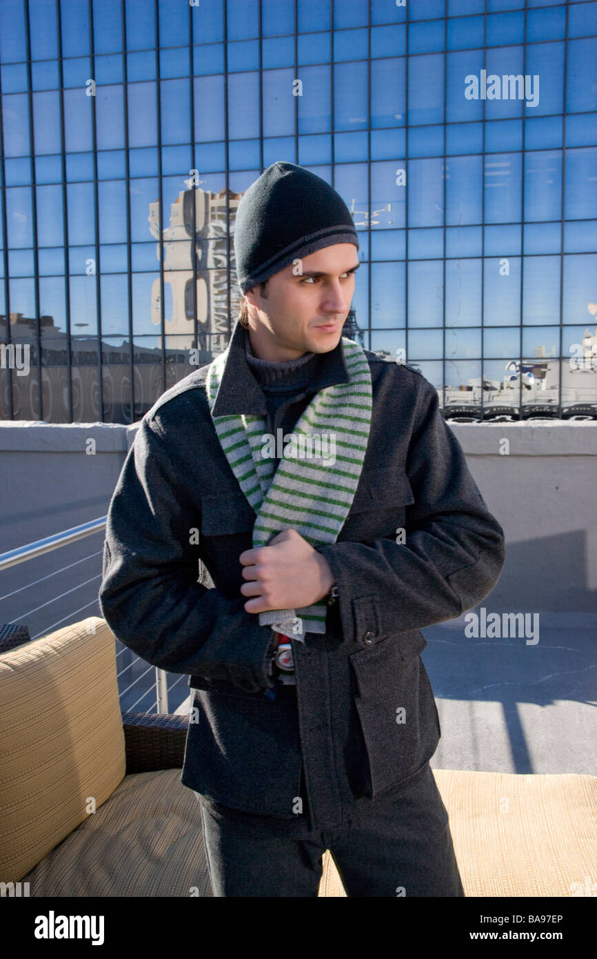 Young man in winter clothing standing on rooftop of downtown condo in ...