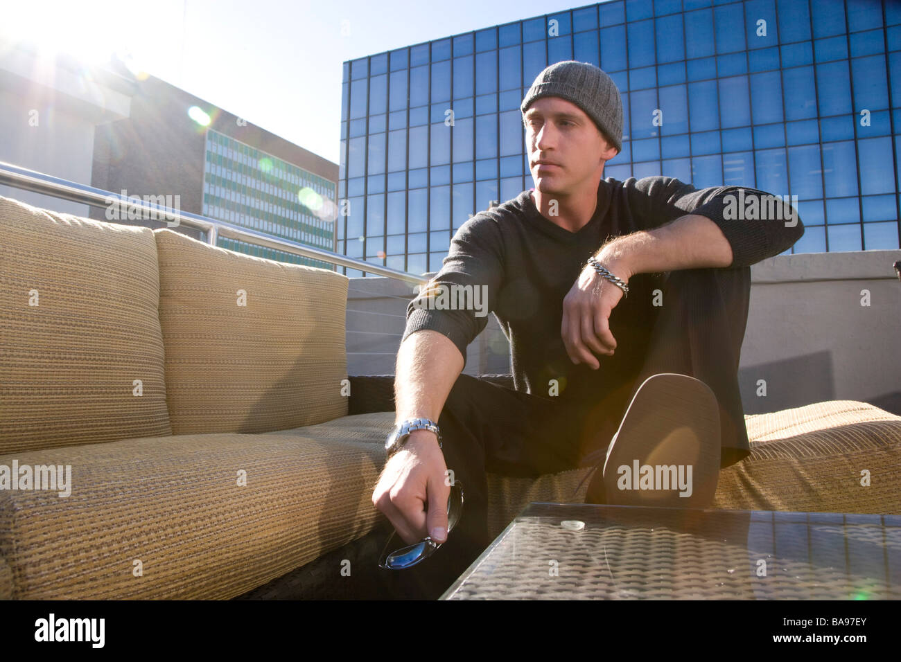Young thoughtful man sitting on rooftop of downtown condo in city Stock ...