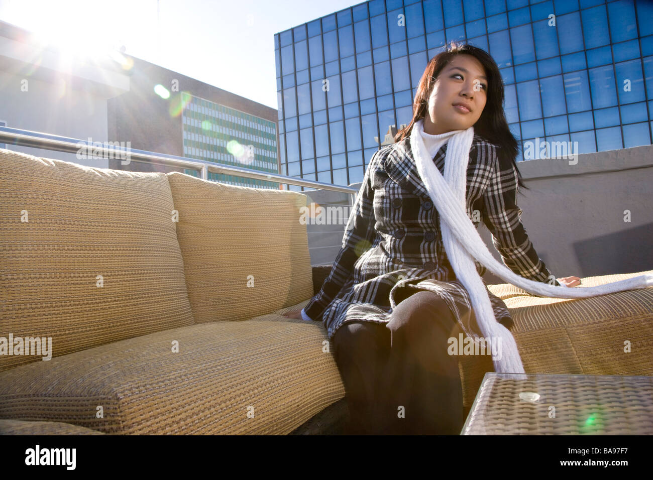 Young Asian woman sitting on rooftop of downtown condo in city Stock ...