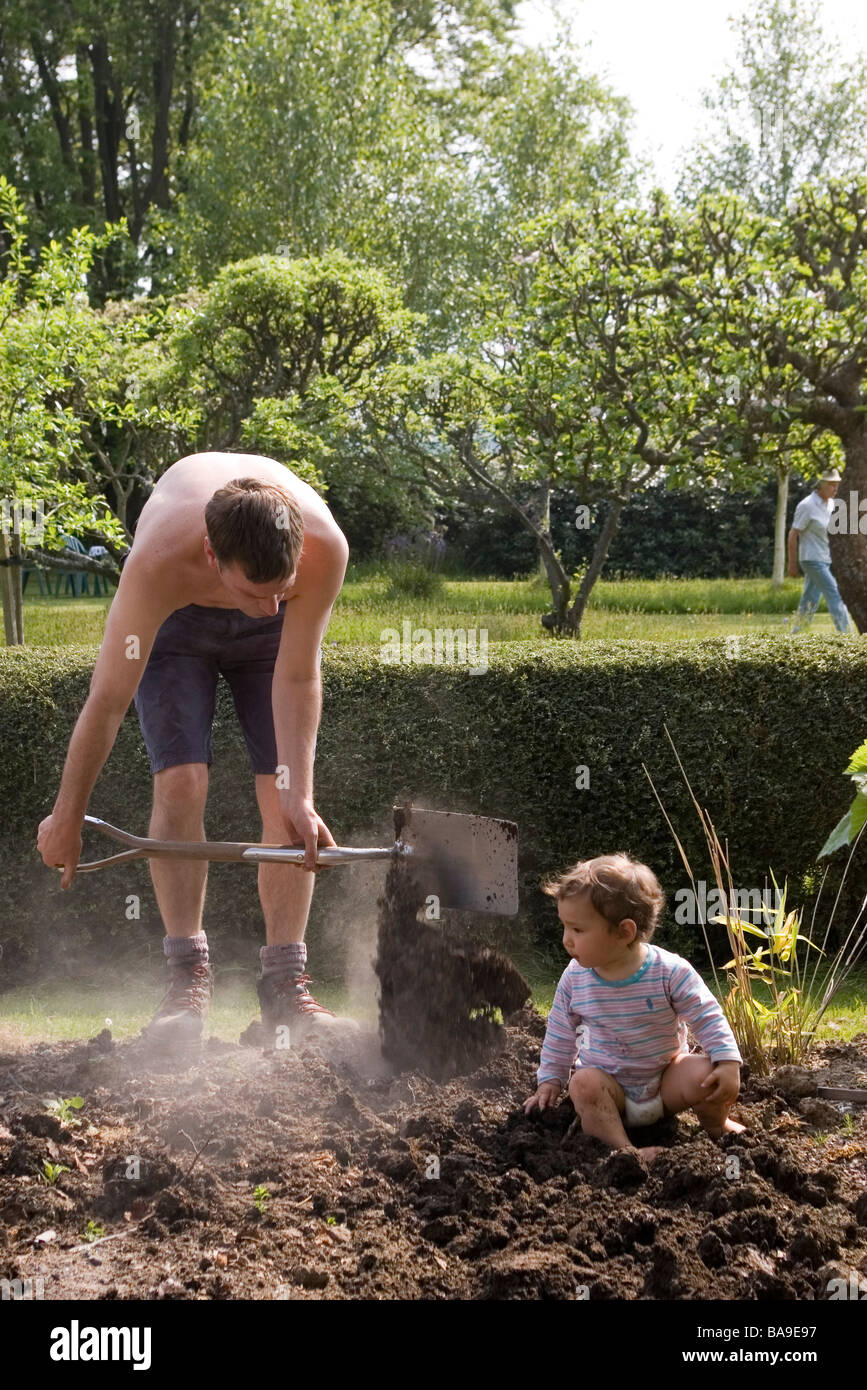 Father and son digging at green vegetable garden for organic home grown ...