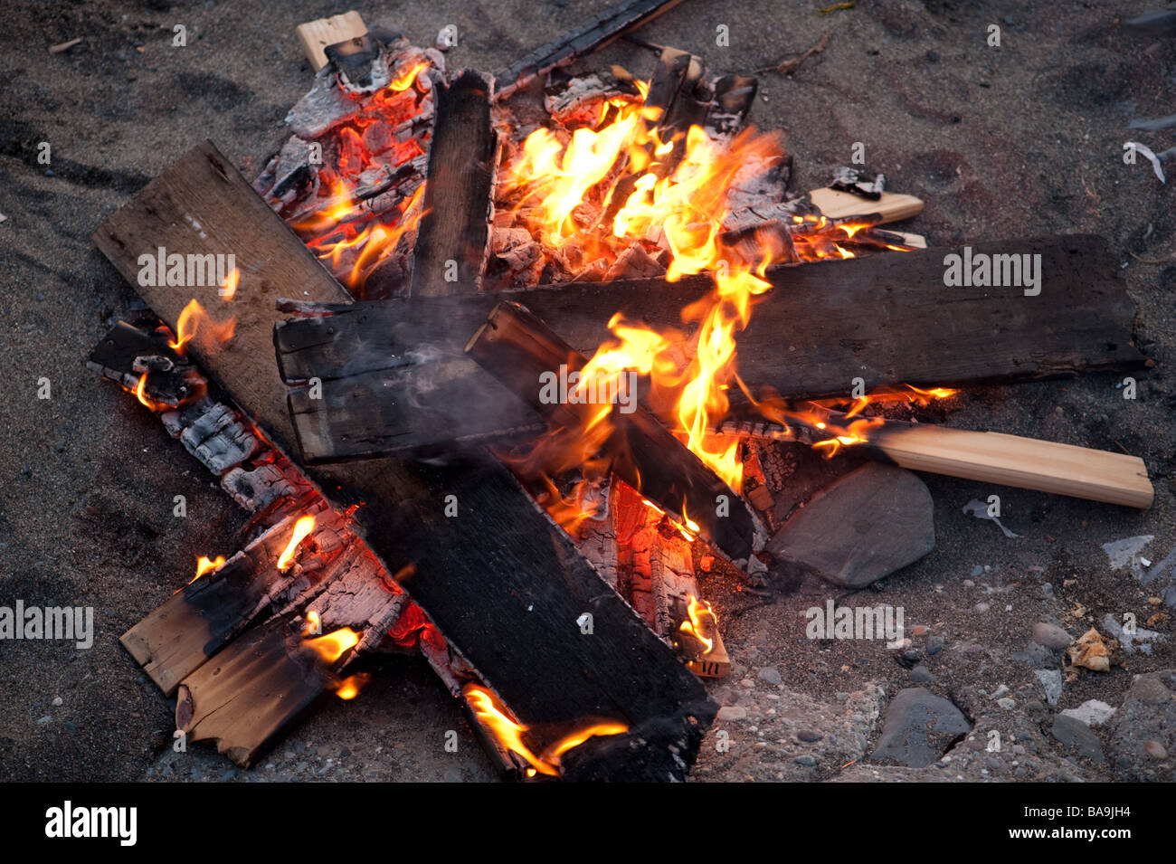 planks of wood burning on a fire on a beach Stock Photo - Alamy