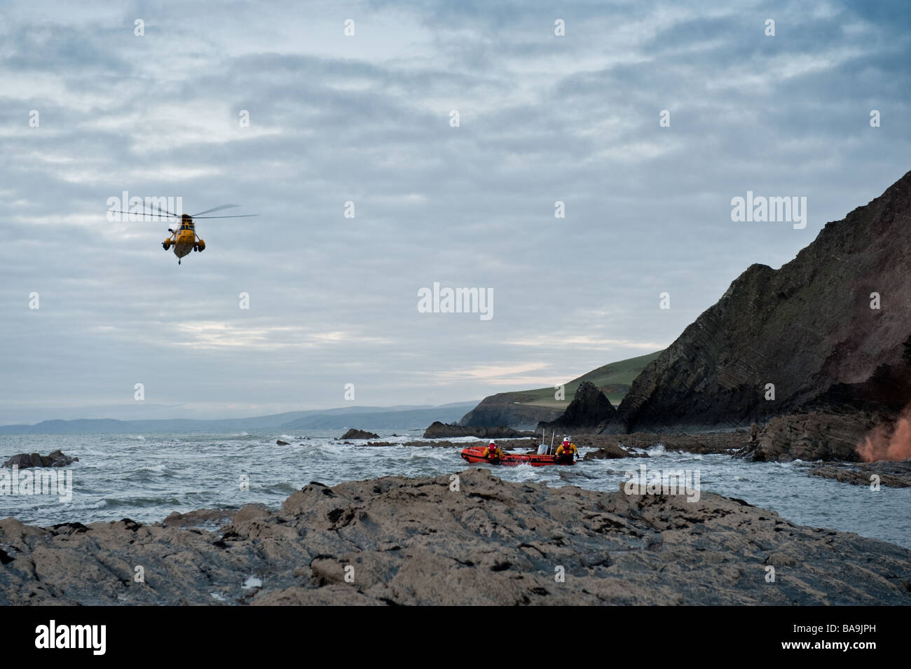 A Sea King helicopter and RNLI inshore lifeboat rescuing a young man ...