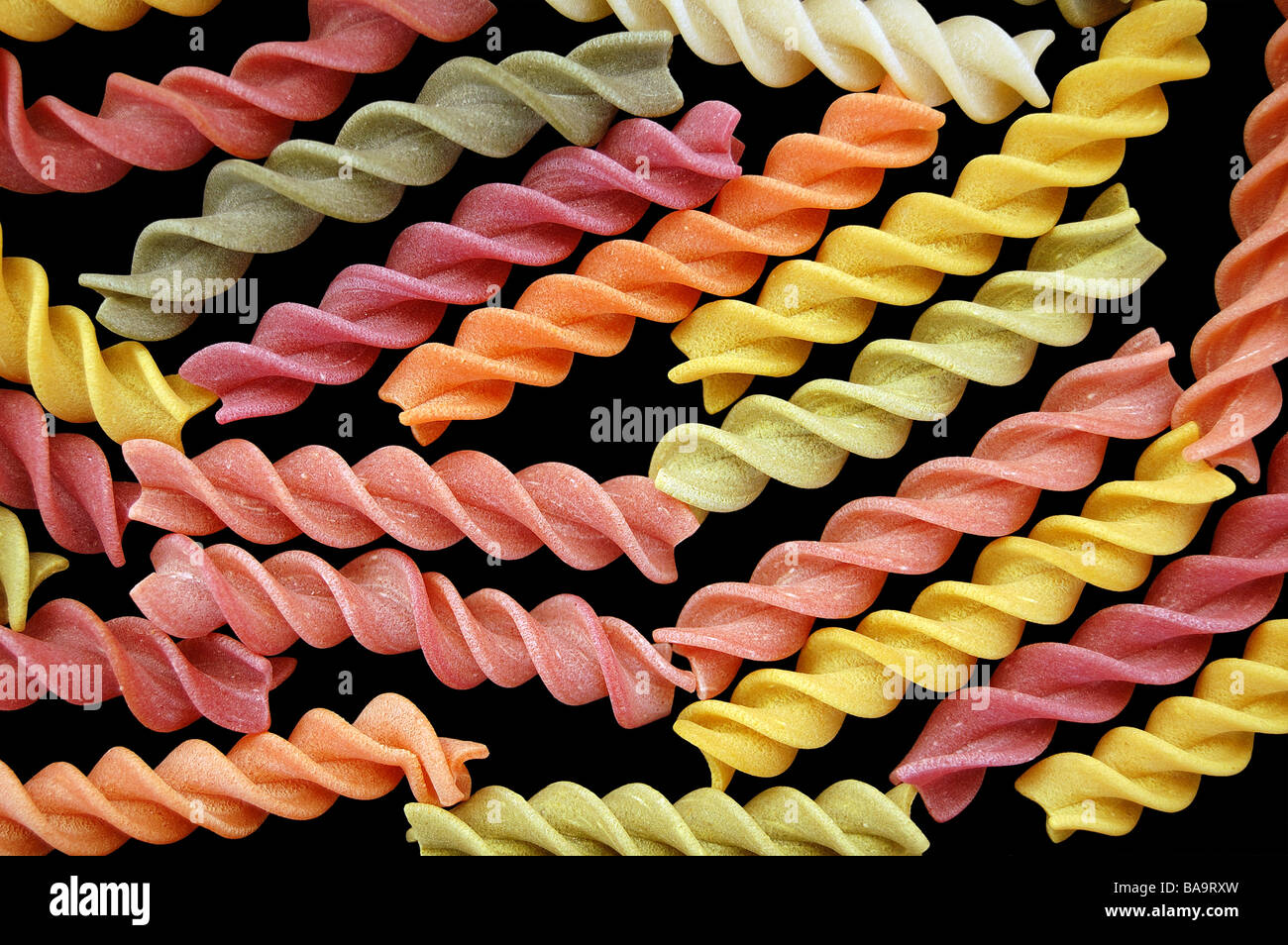 Different flavors of fusilli twists pasta against a black background ...