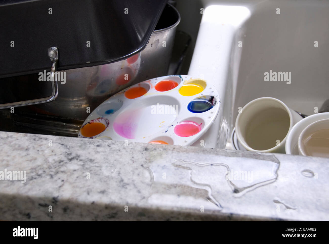 Kitchen sink with dishes, pots and pans, and a water color tray with ...