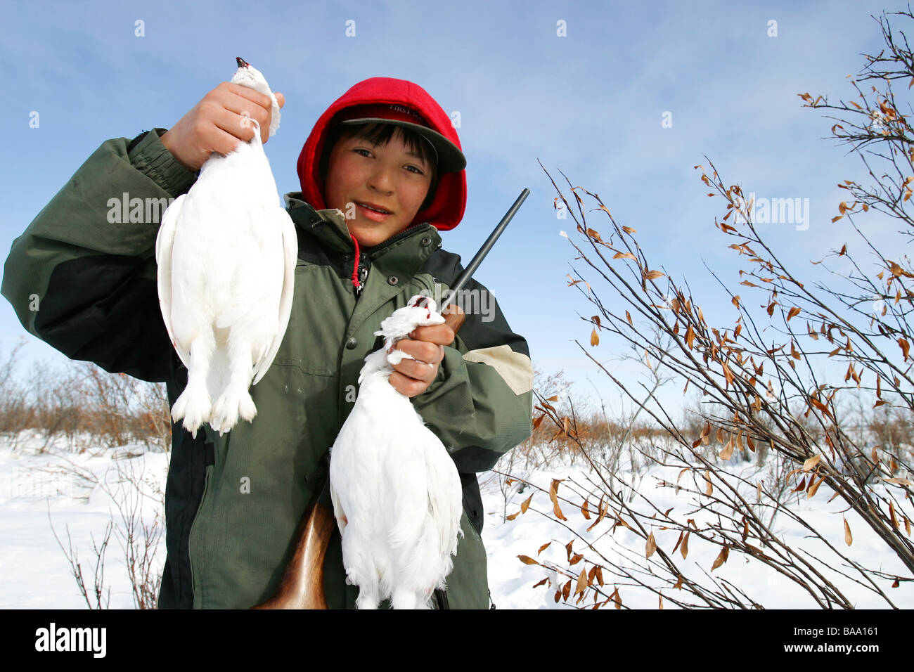 A young First Nations hunter holds up ptarmigan game birds near Old ...