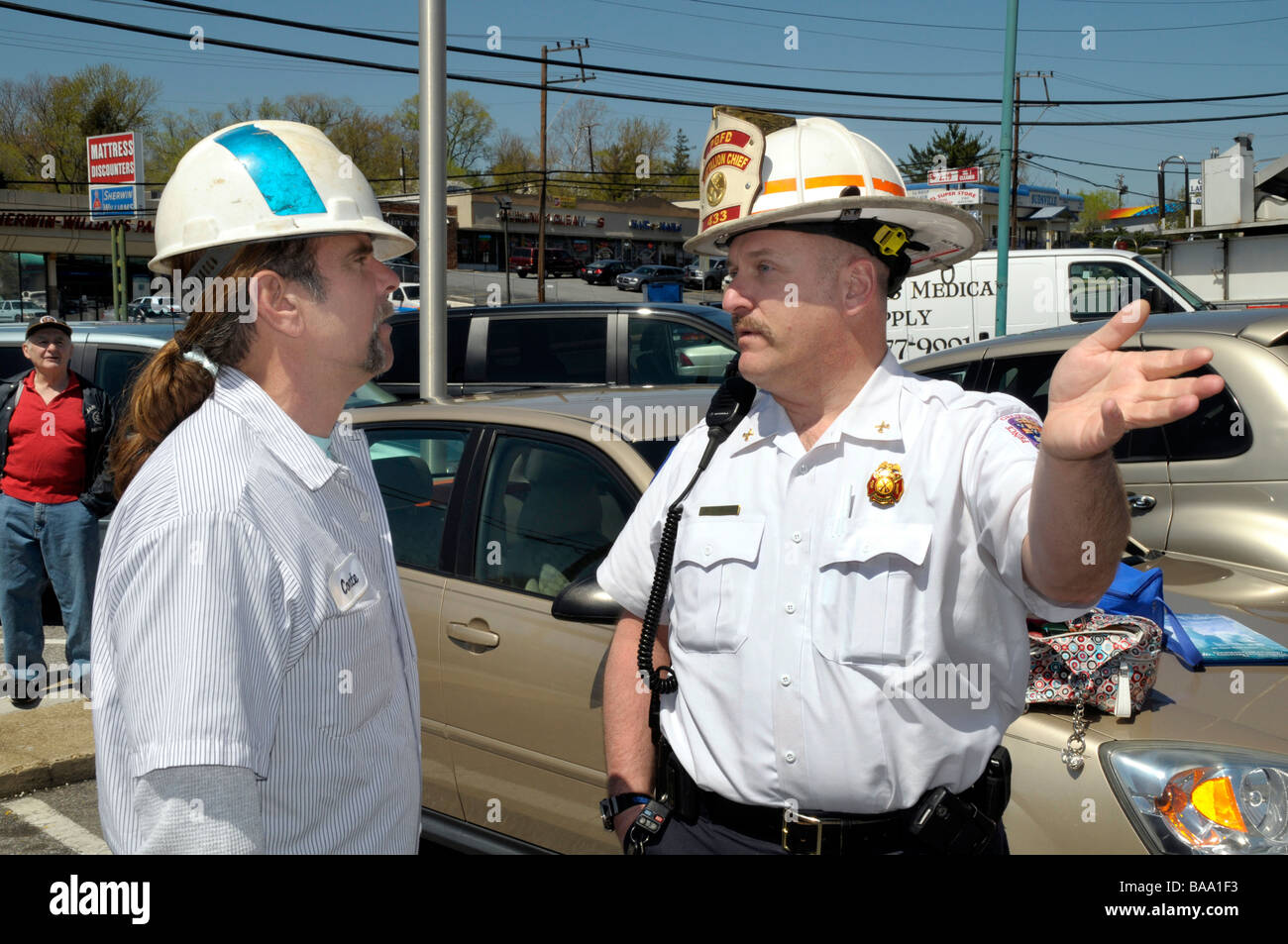 Battalion fire chief talks to utility worker at the scene of an ...
