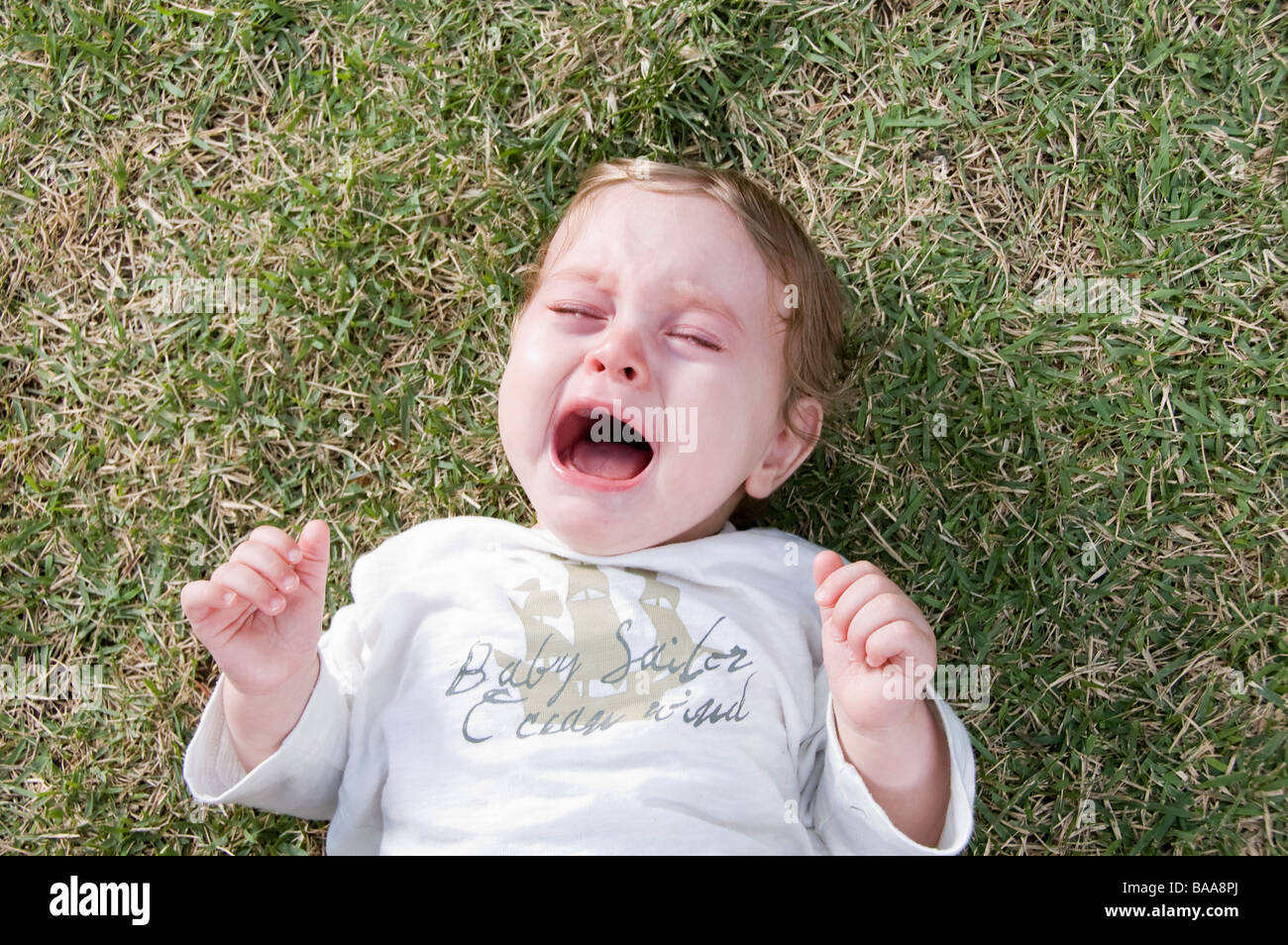 adorable child crying and lying in the garden Stock Photo - Alamy