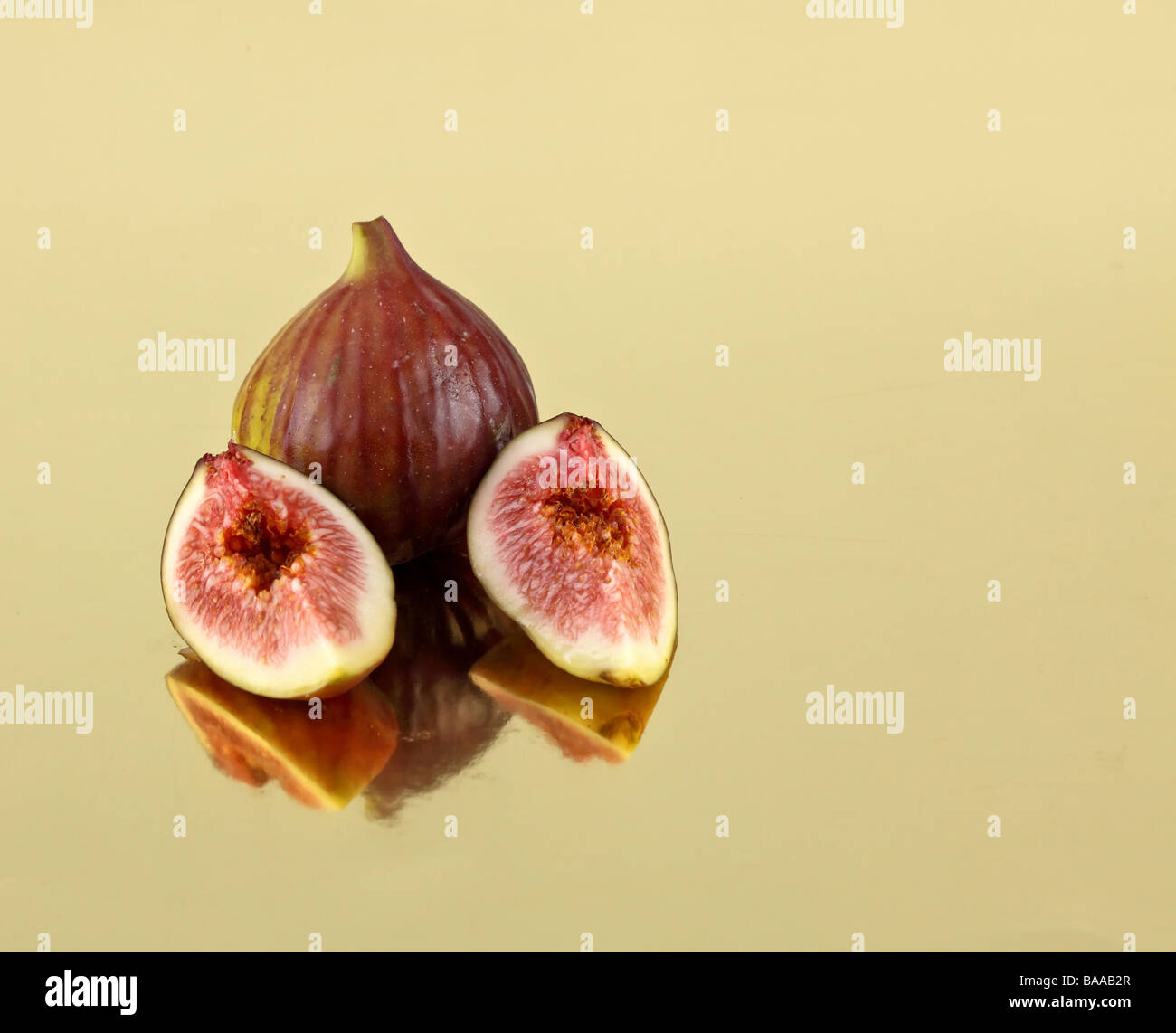 Figs arranged on a golden background with one fig sliced into segments ...