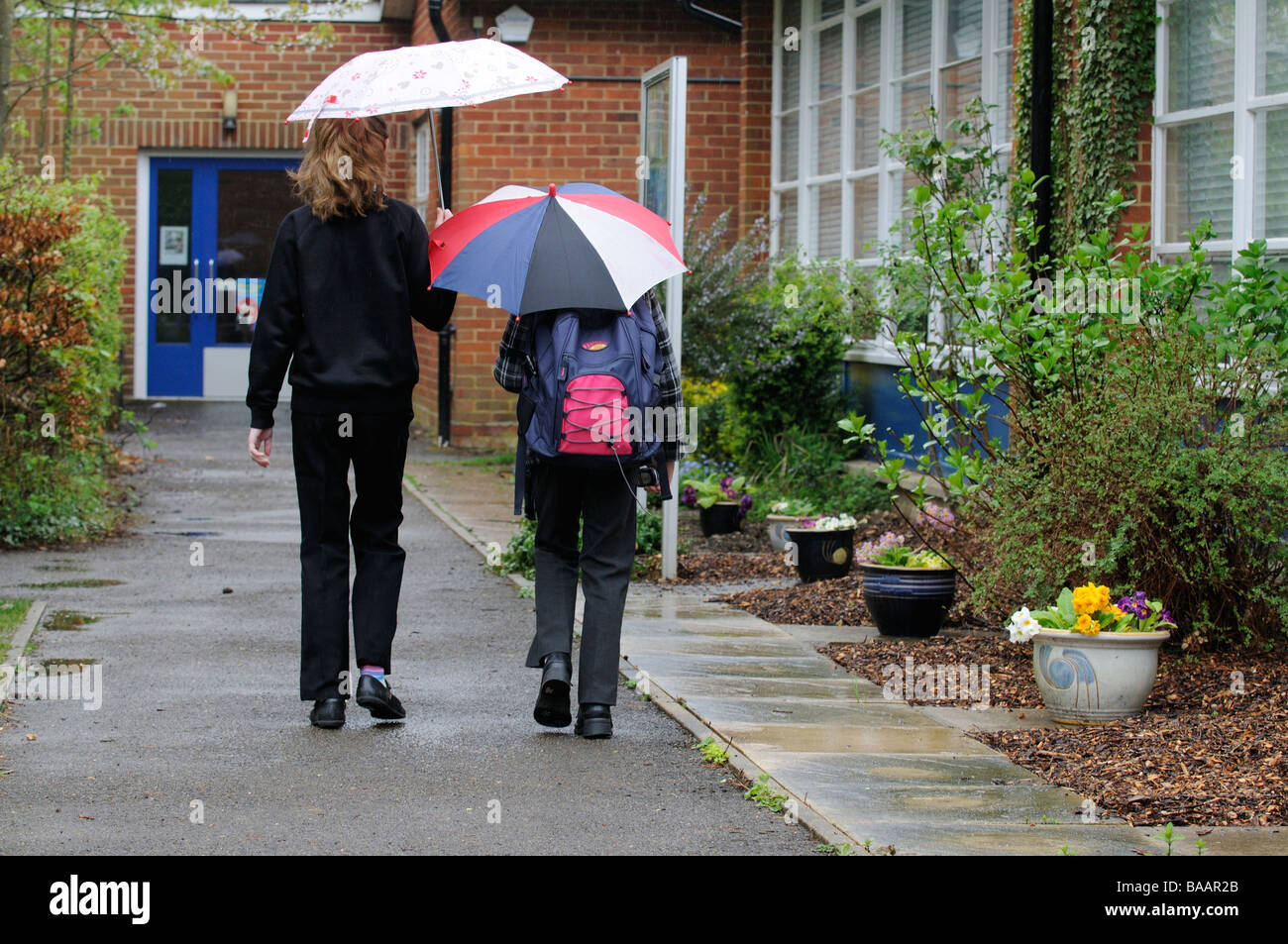 Walking to school in the rain two pupils holding umbrellas Stock Photo ...