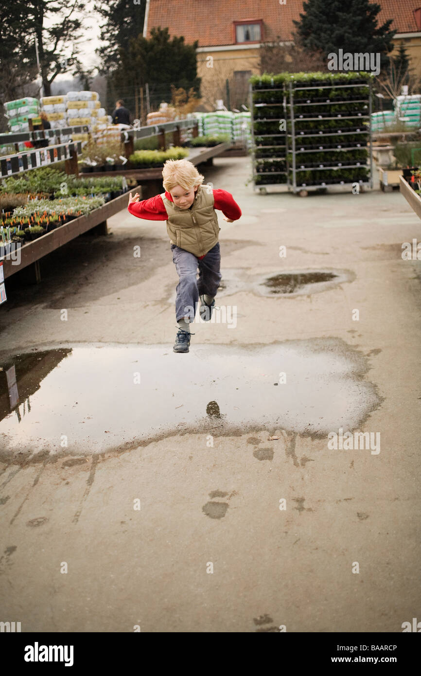 A blond boy jumping over a puddle of water, Sweden Stock Photo - Alamy