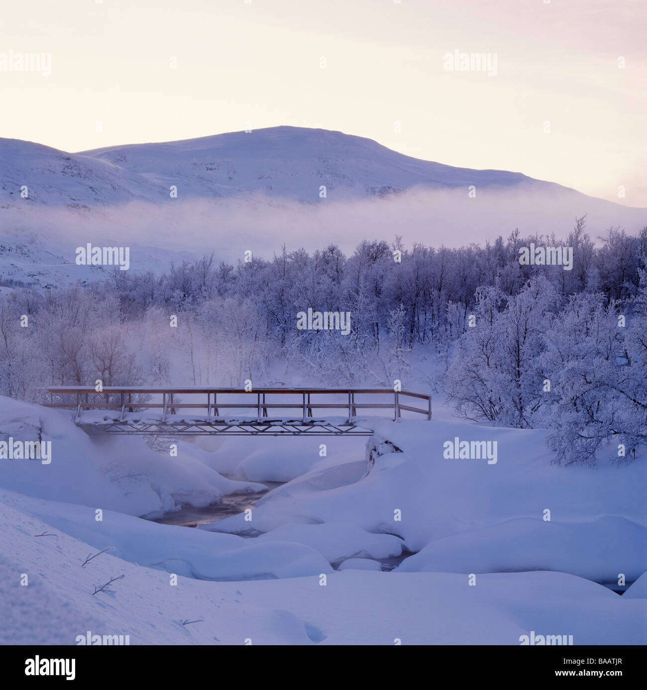 Snow-covered bridge with trees and mountains in background Stock Photo ...