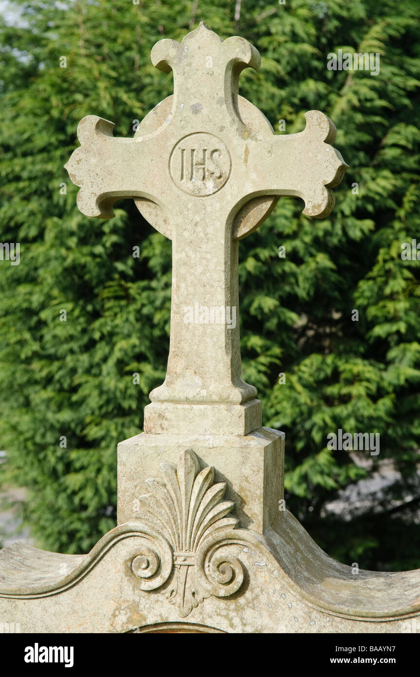 Carved stone cross on top of a gravestone marked "IHS Stock Photo - Alamy