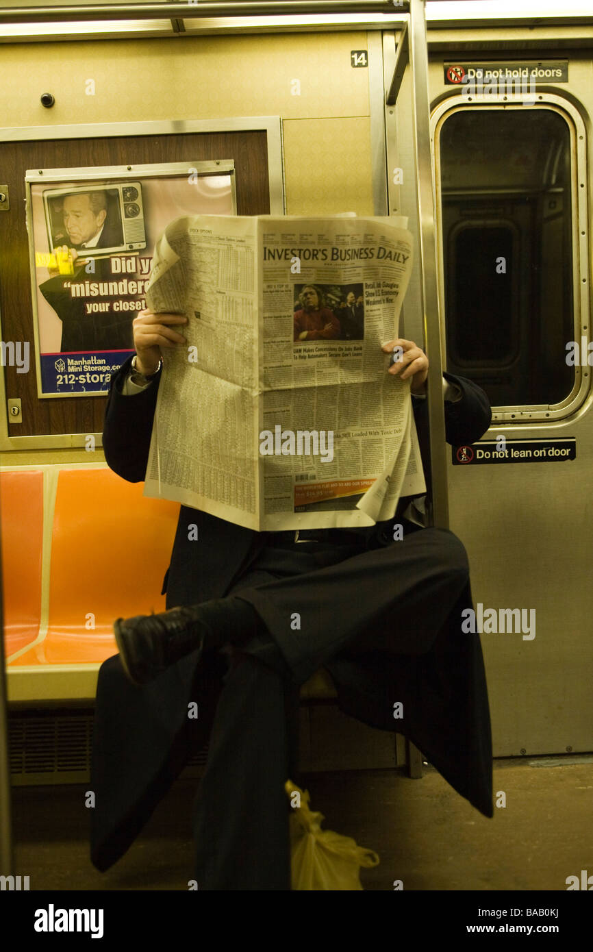Man reads the Investors Daily Newspaper on a subway train in NYC to ...