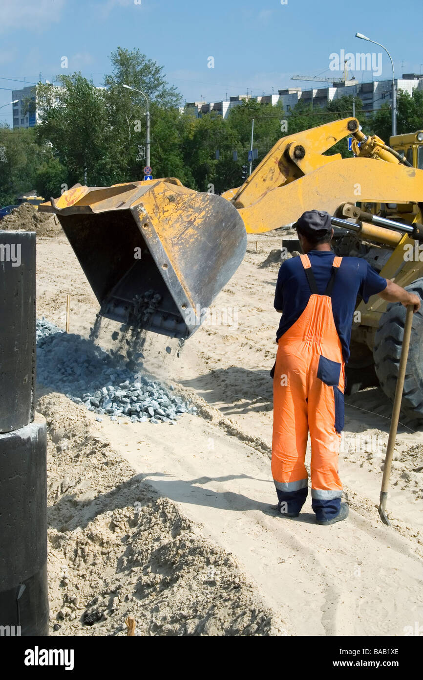 Worker and road loader on construction of road Stock Photo - Alamy