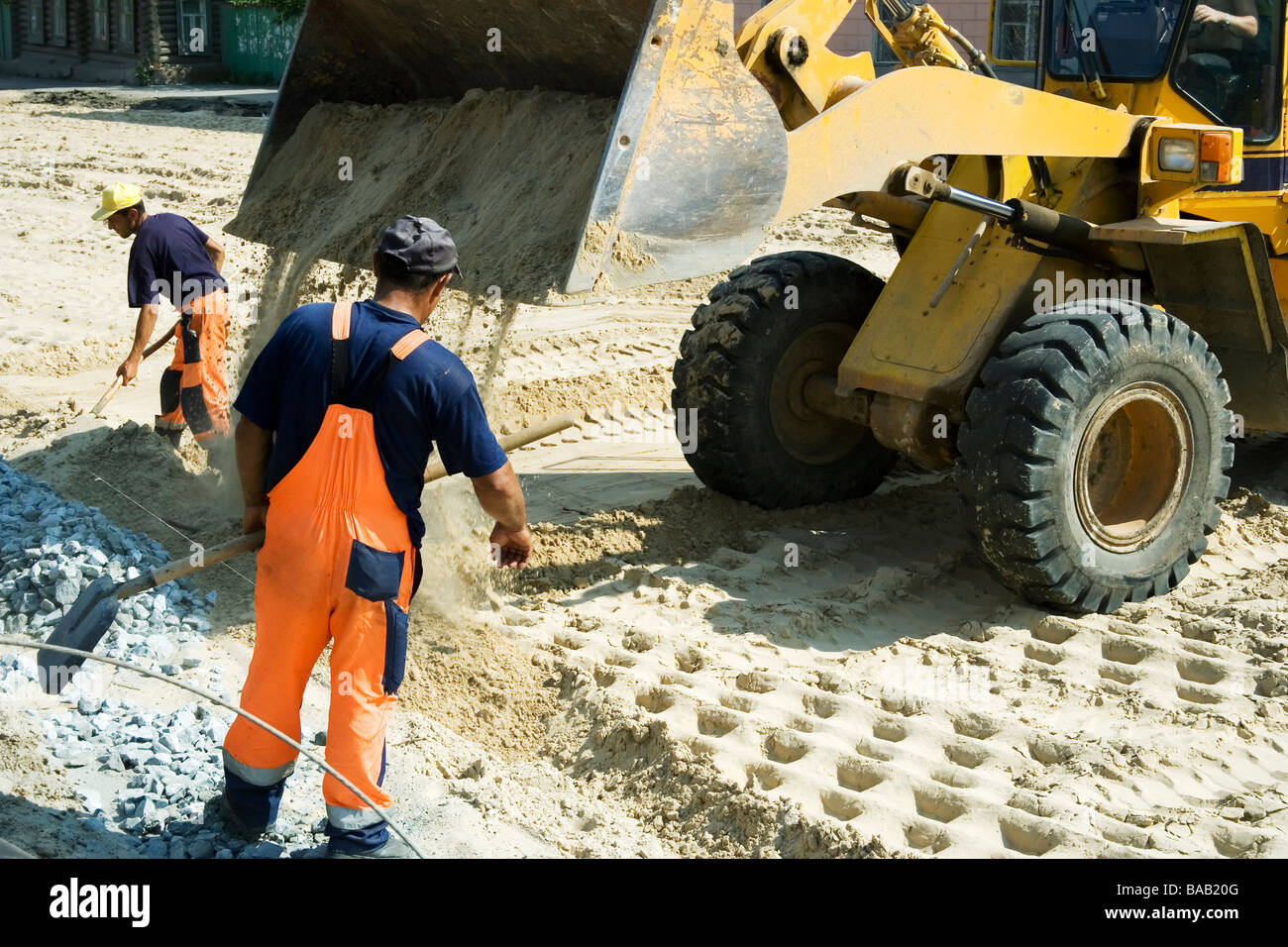 Worker and road loader on the construction of road Stock Photo - Alamy