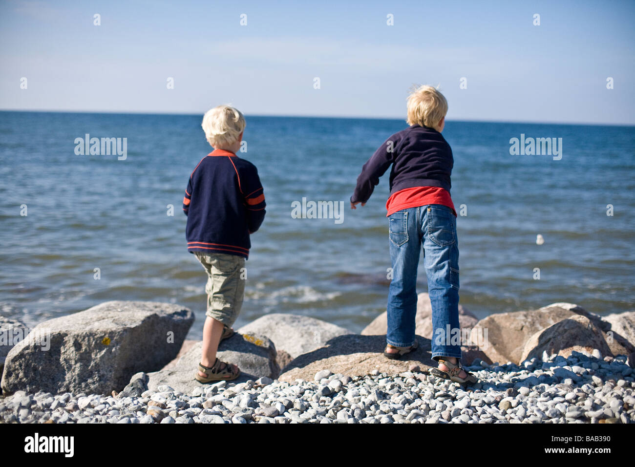Two boys throwing stones into the water, Gotland, Sweden Stock Photo ...