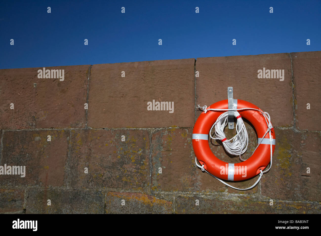 brand new bright red lifebelt with white rope hanging on a hanger on ...