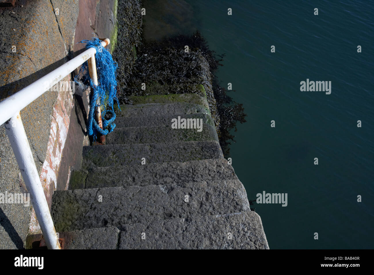 stone steps with white handrail leading down a harbour wall into the ...