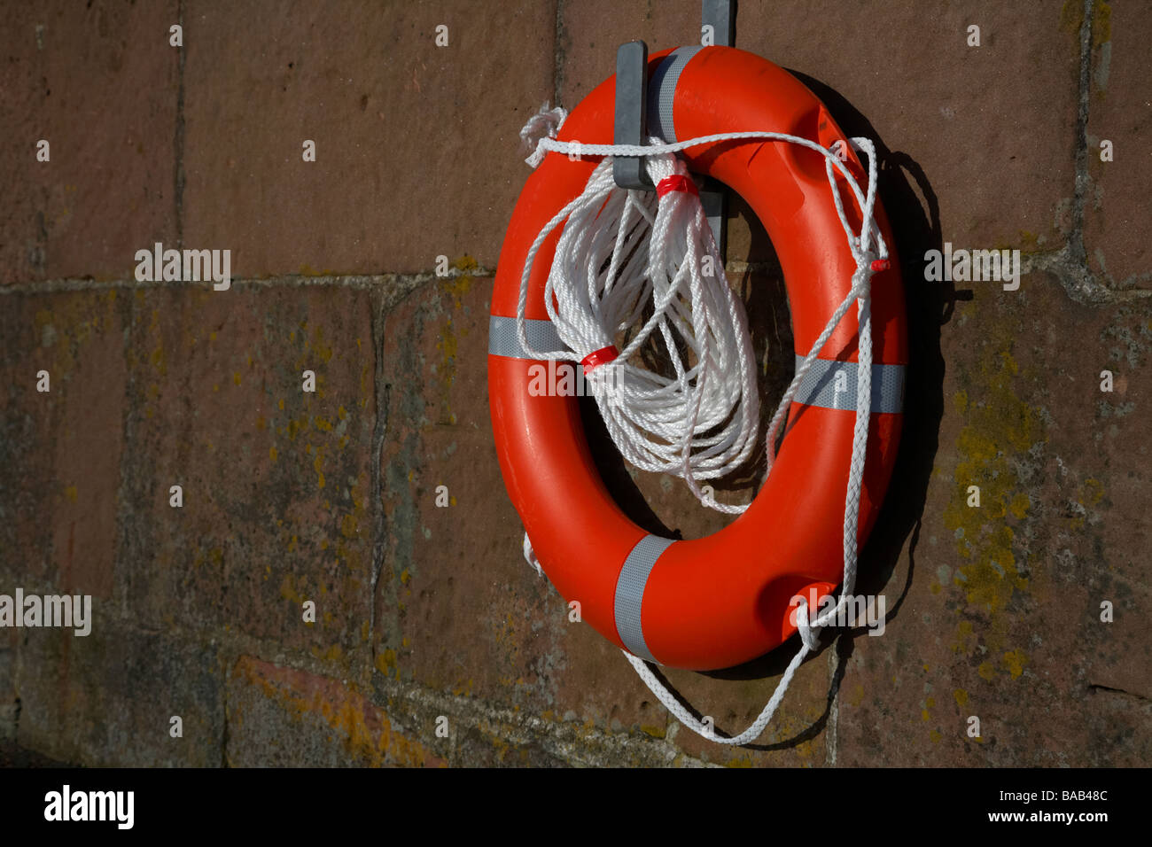 brand new bright red lifebelt with white rope hanging on a hanger on ...