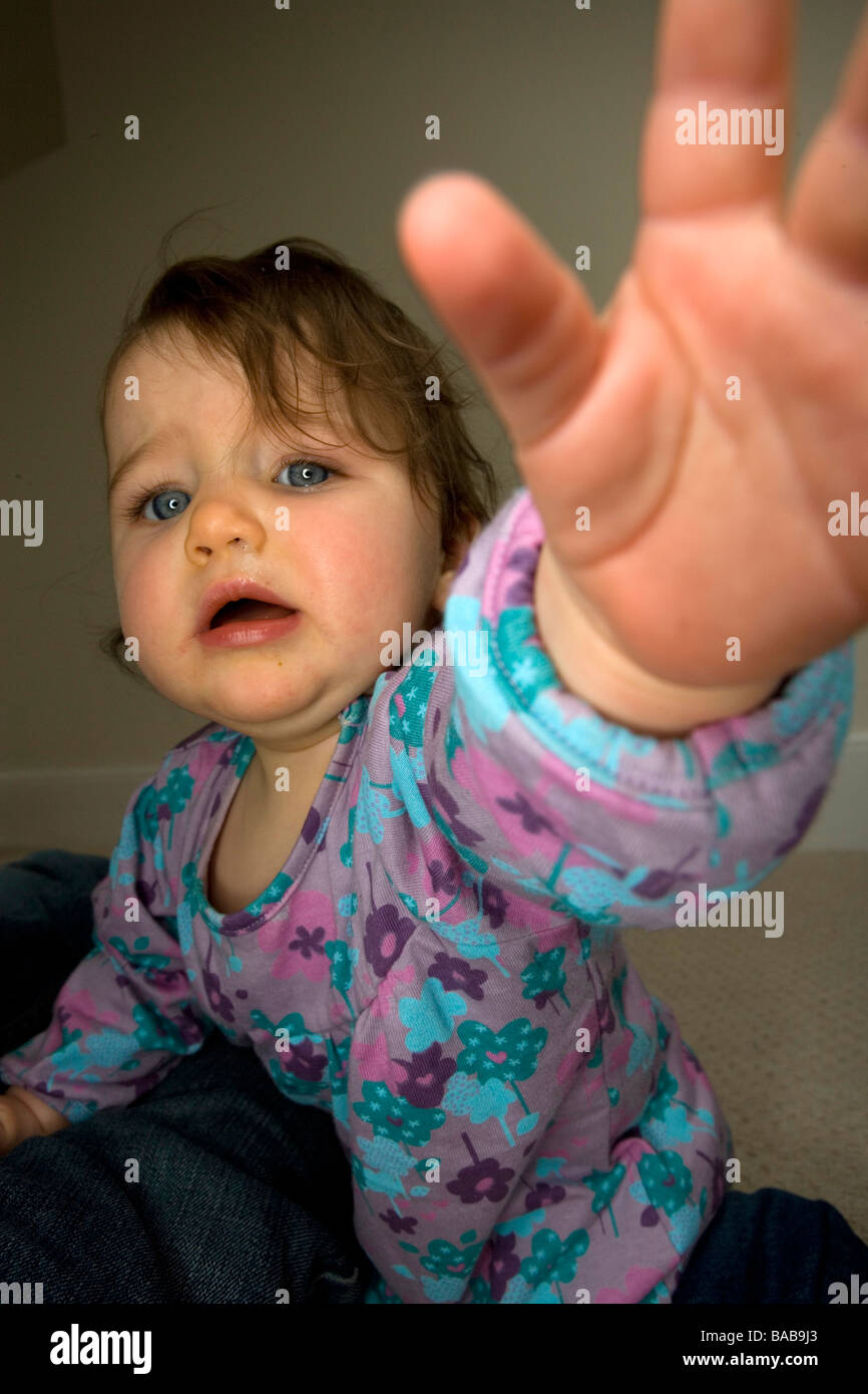A eight month old baby girl reaches out to grab something Stock Photo ...