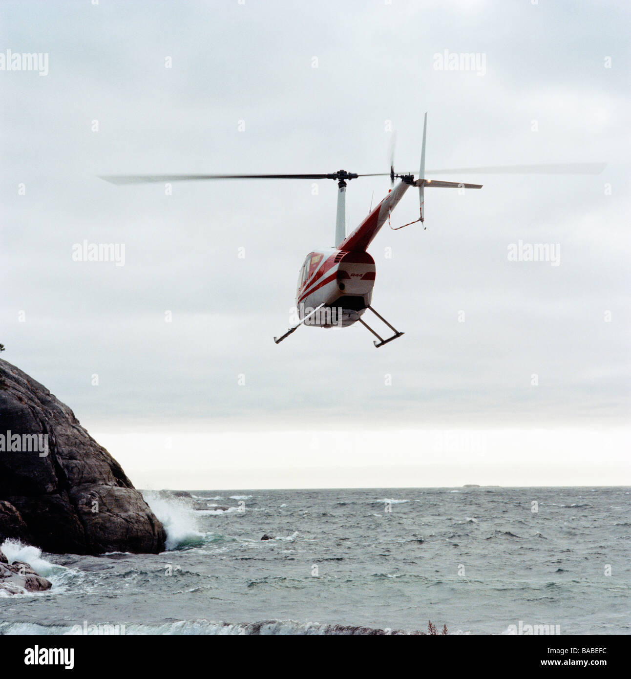 A helicopter flying over an ocean and cliffs Stock Photo - Alamy