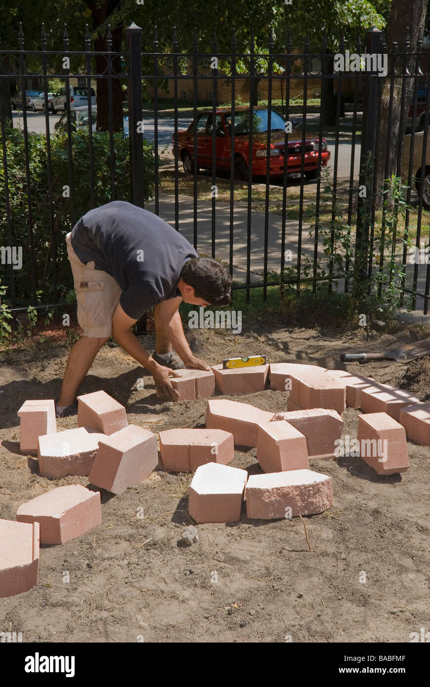 Hispanic/Italian landscaping architect laying pavers for raised flower ...