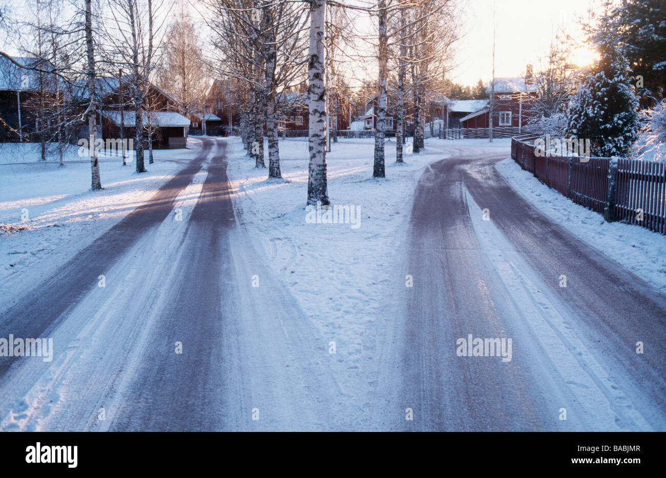 Snow-covered road intersection with houses in background Stock Photo ...