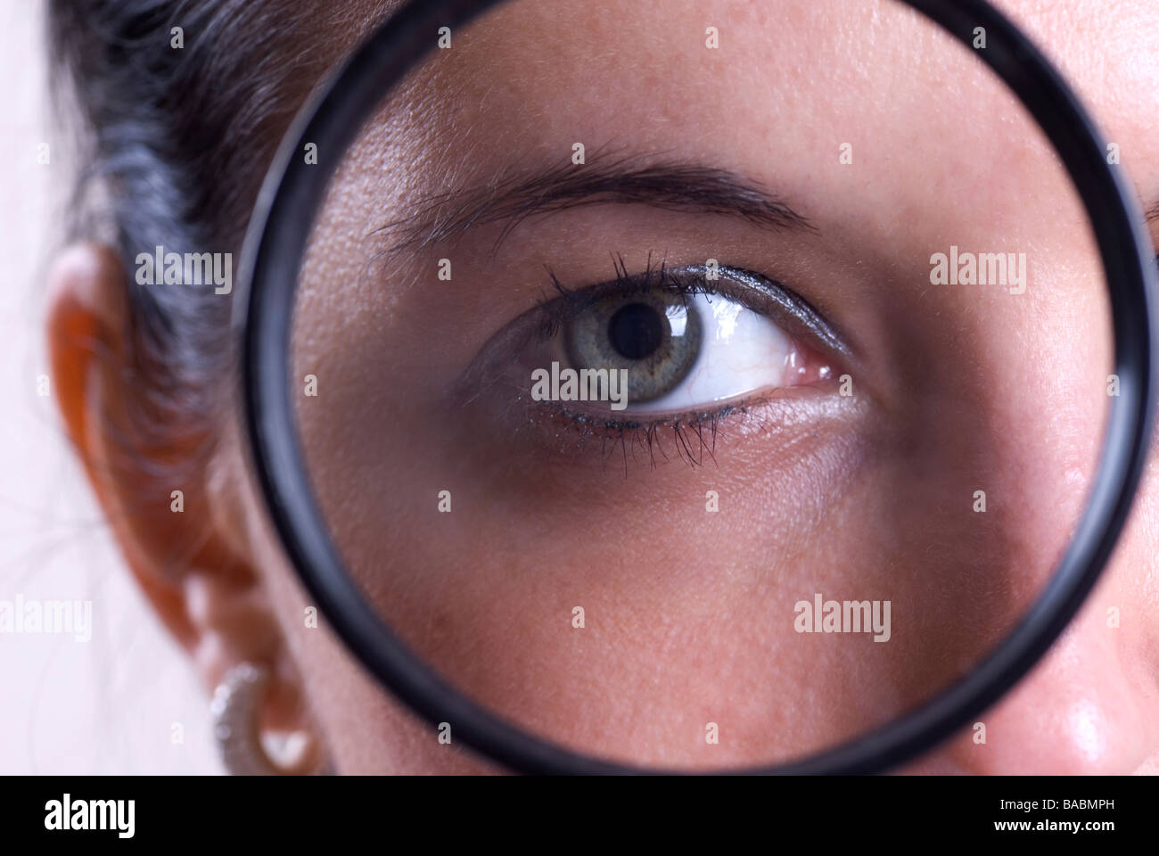 Close up of a woman looking through a magnifying glass Stock Photo - Alamy