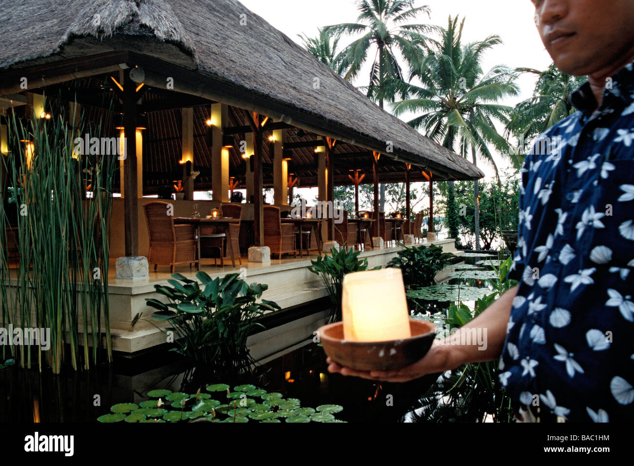 Indonesia, Bali, Alila Manggis Resort, waiter carrying a candle near ...