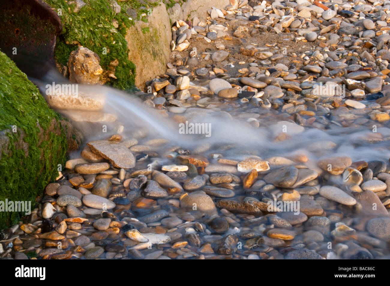 Silky smooth water running over pebbles bathed in morning sunlight ...