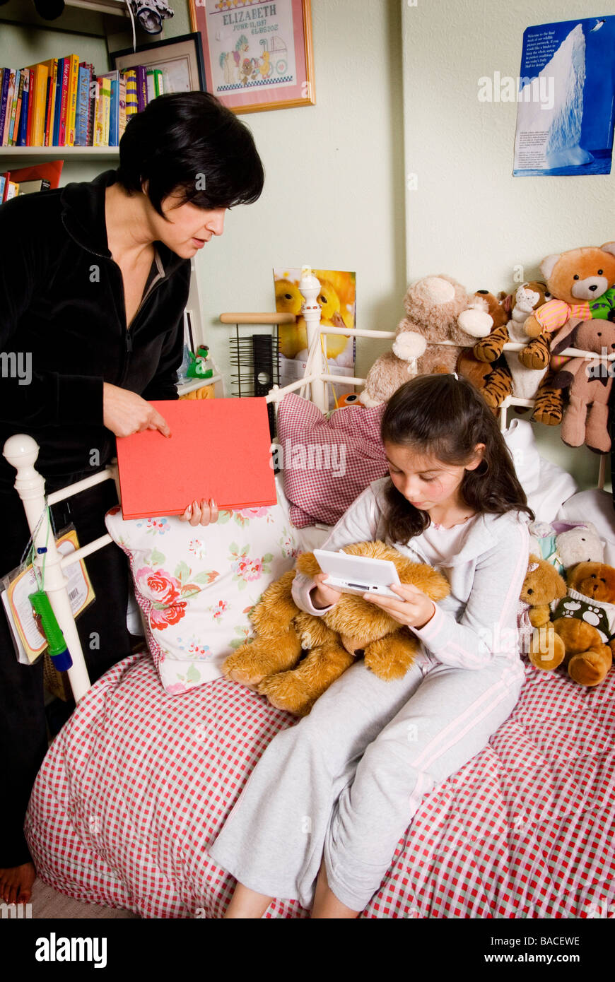 Girl operating a personal data assistant with her mother standing ...