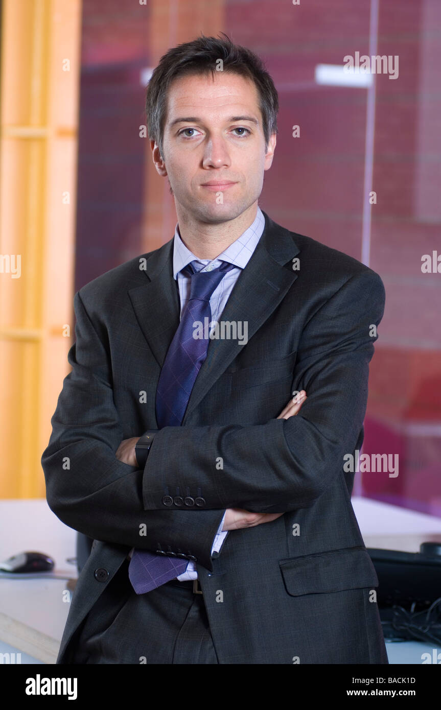 Businessman leaning against a table in an office Stock Photo - Alamy