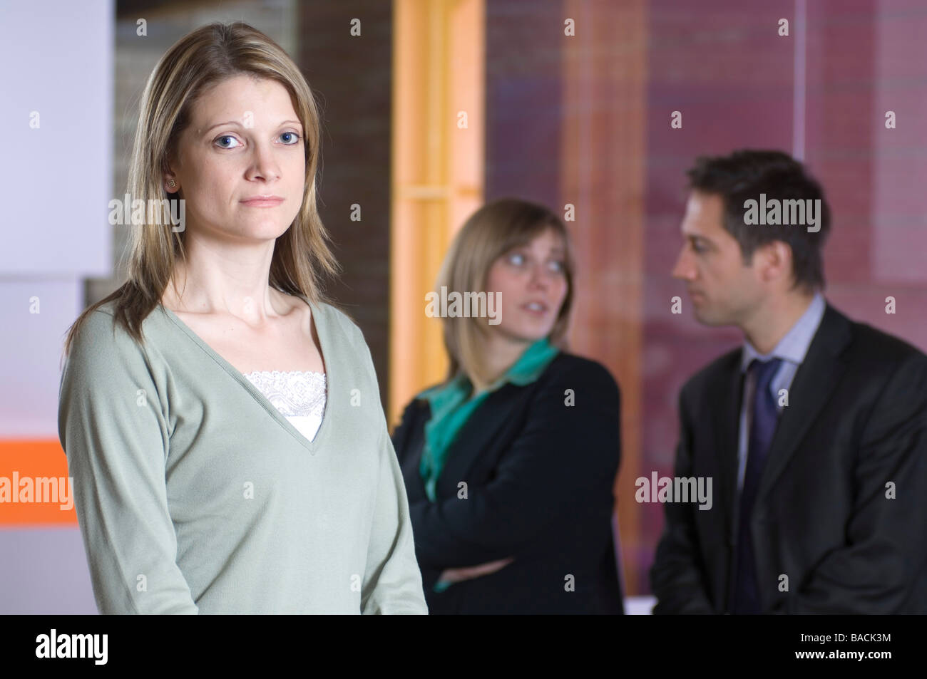 Businesswoman standing in an office with two business executives in the ...